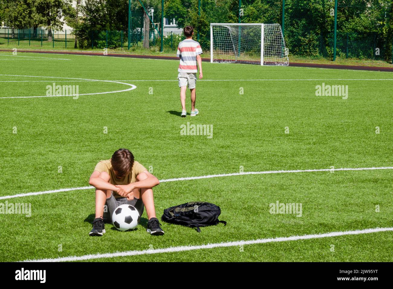 Sad disappointed teenage boy sitting in empty school sport stadium ...