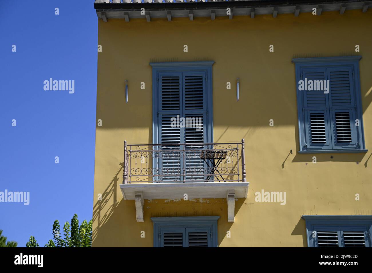 Old Neoclassical house facade with an ochre stucco wall and grey wooden ...