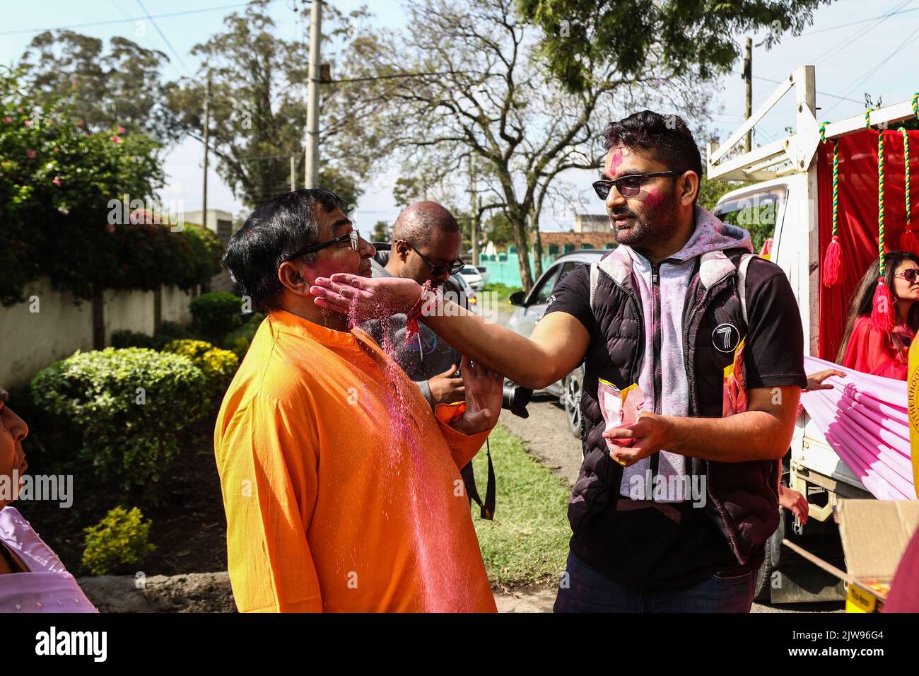 A devotees paints his colleague with powdered color during the Ganesh ...