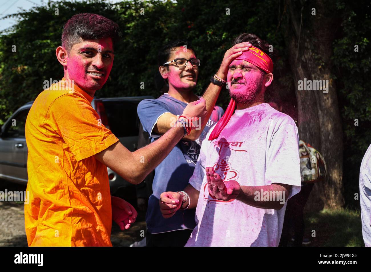 Devotees paint their colleague with powdered color during the Ganesh ...