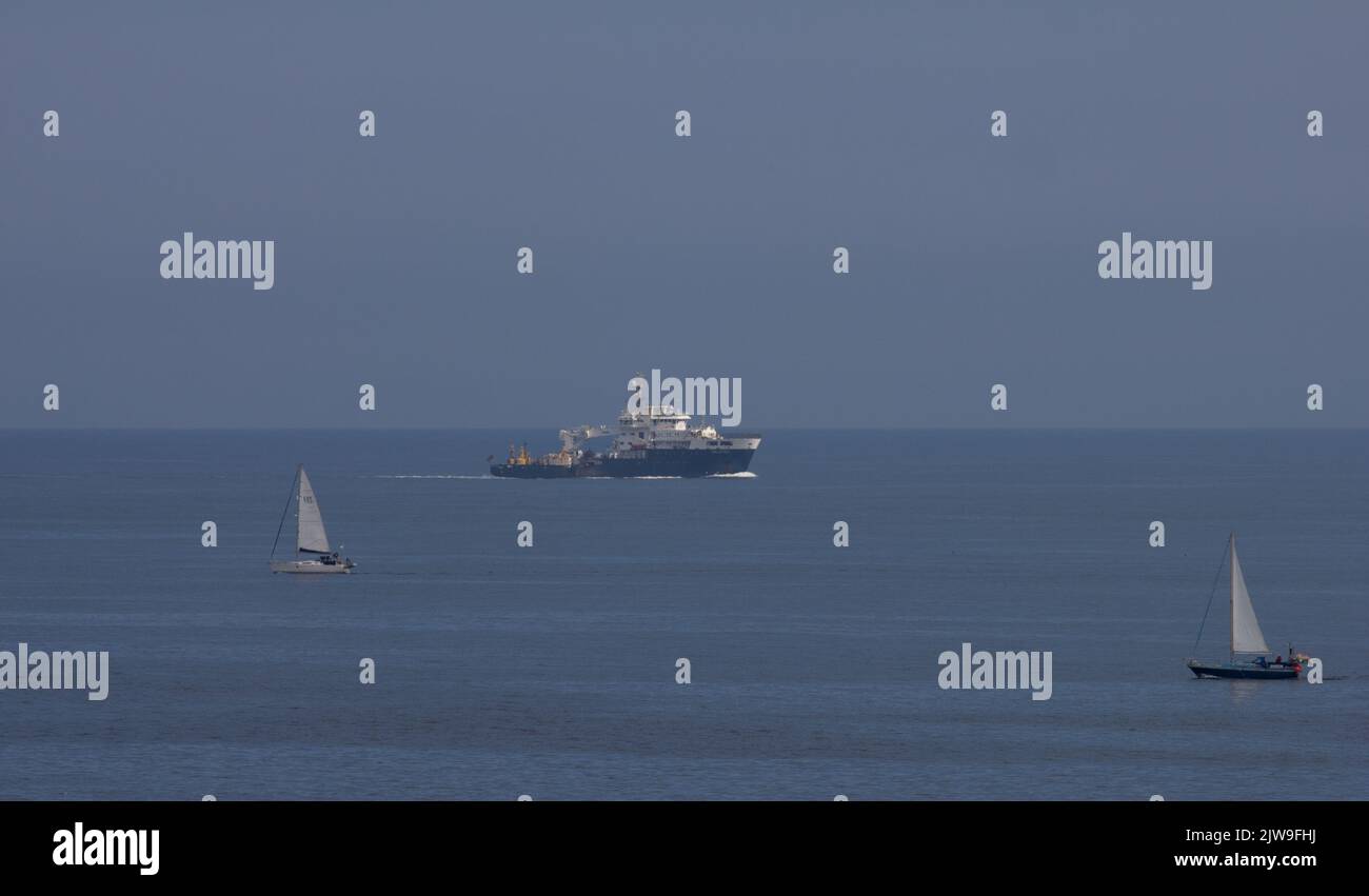 Sail and power. Sailing ships passing a ship in Coverack Bay, Cornwall ...