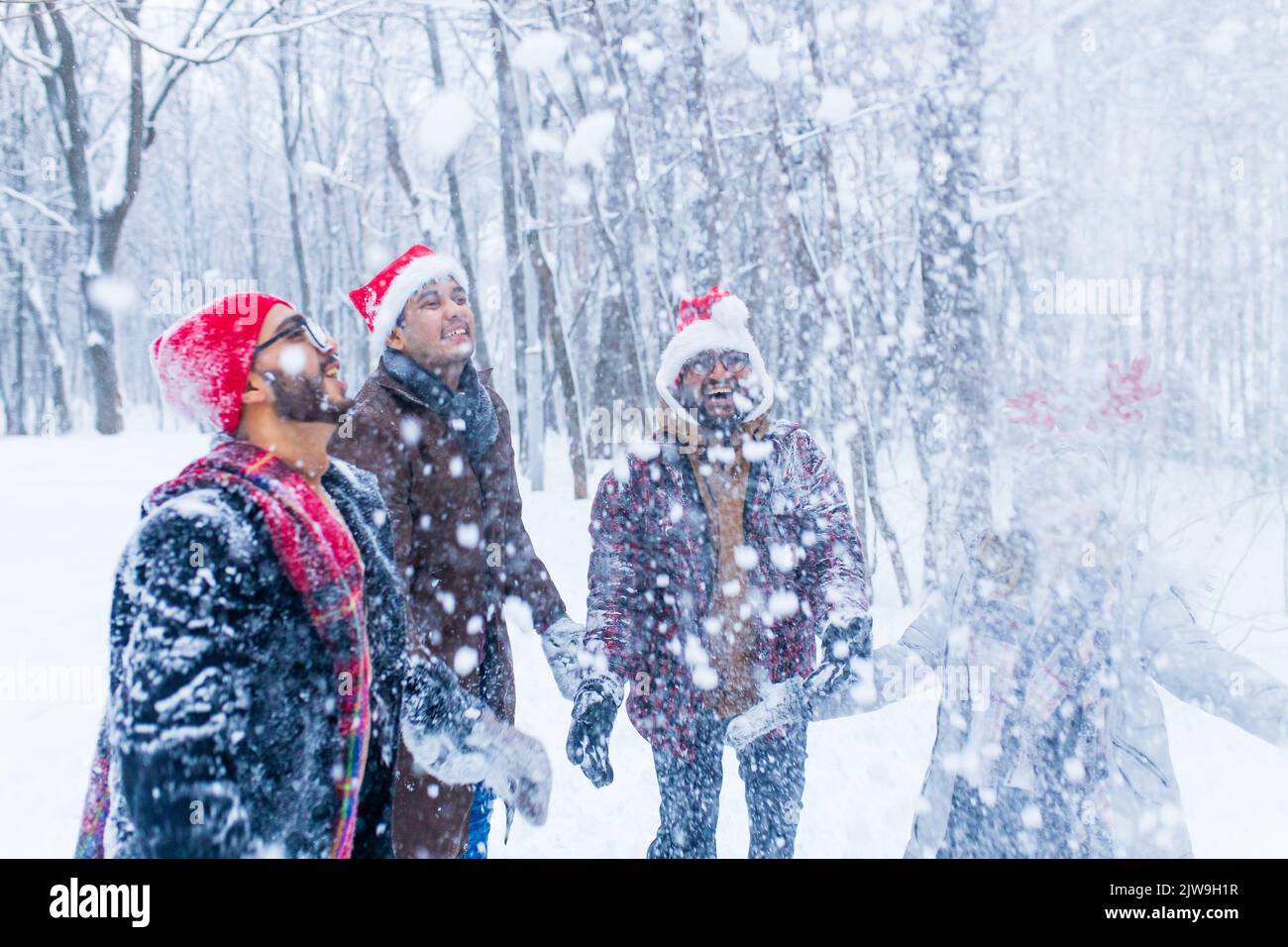 four happy friends are having fun and throwing snow Stock Photo - Alamy