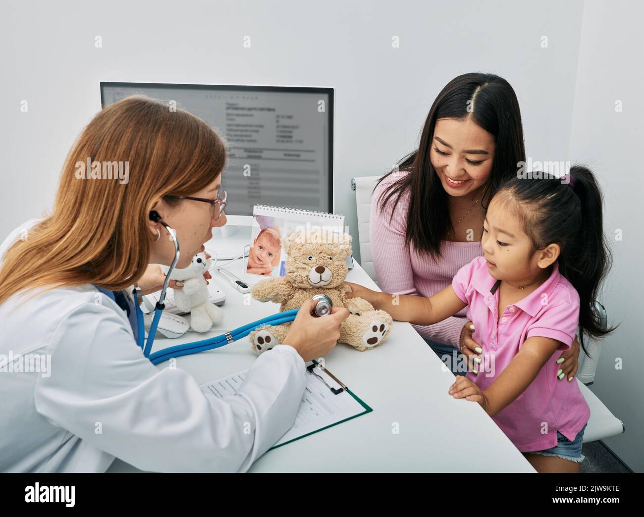 Friendly pediatrician having fun with Korean little patient and her mom ...