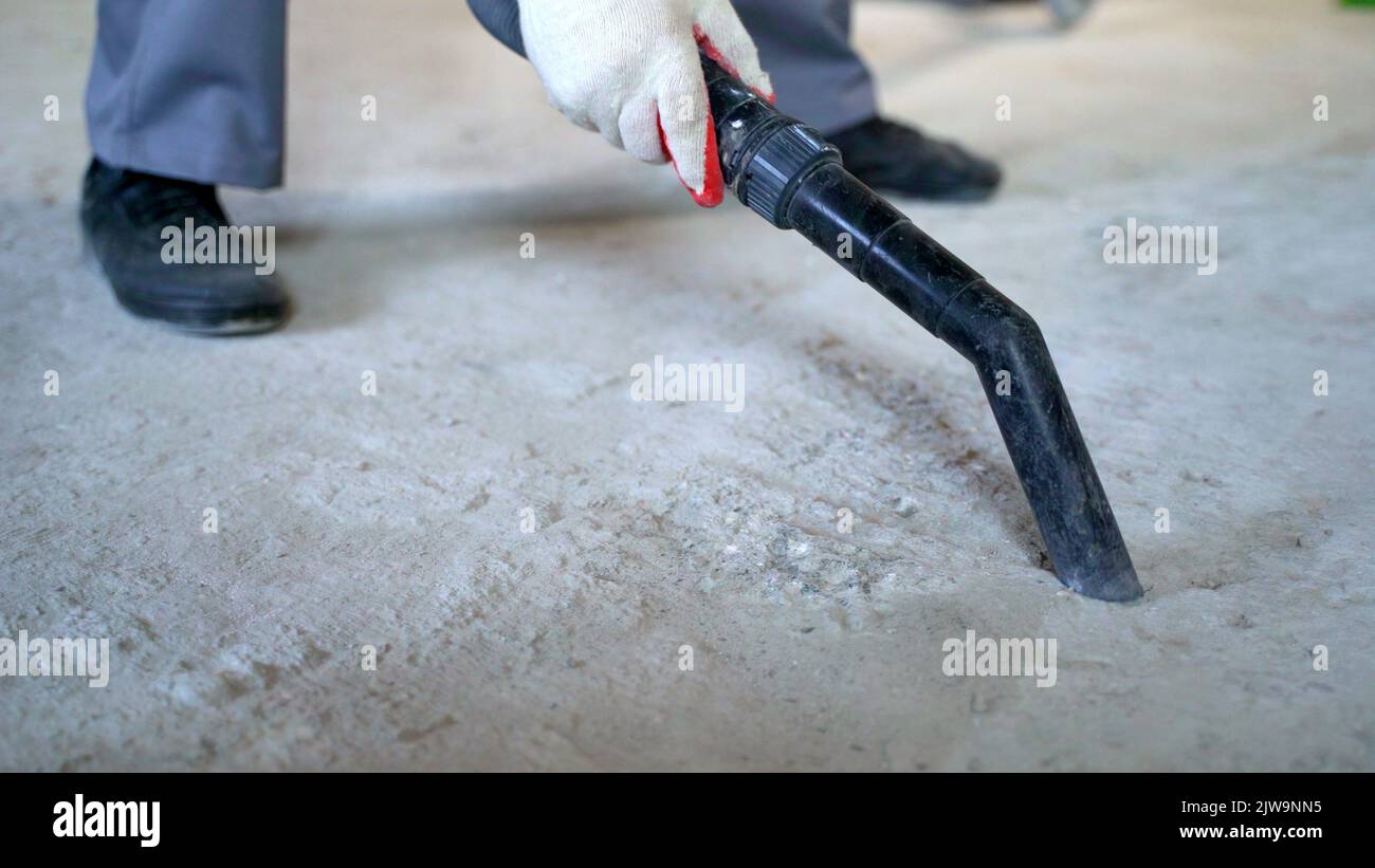 The builder vacuums the concrete floor for further pouring. A worker ...