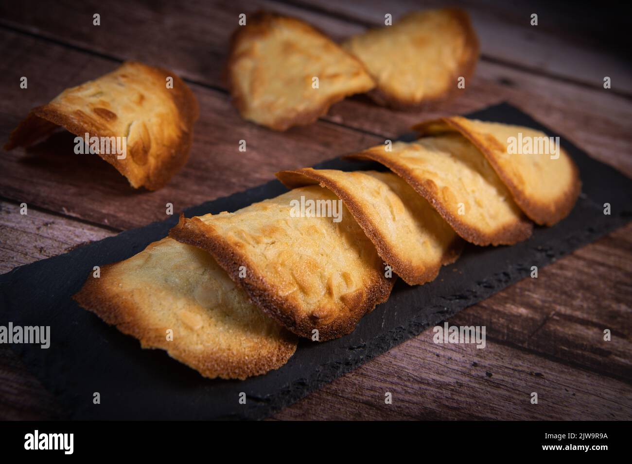French delicacy pastry tuile with almond on wood background Stock Photo ...