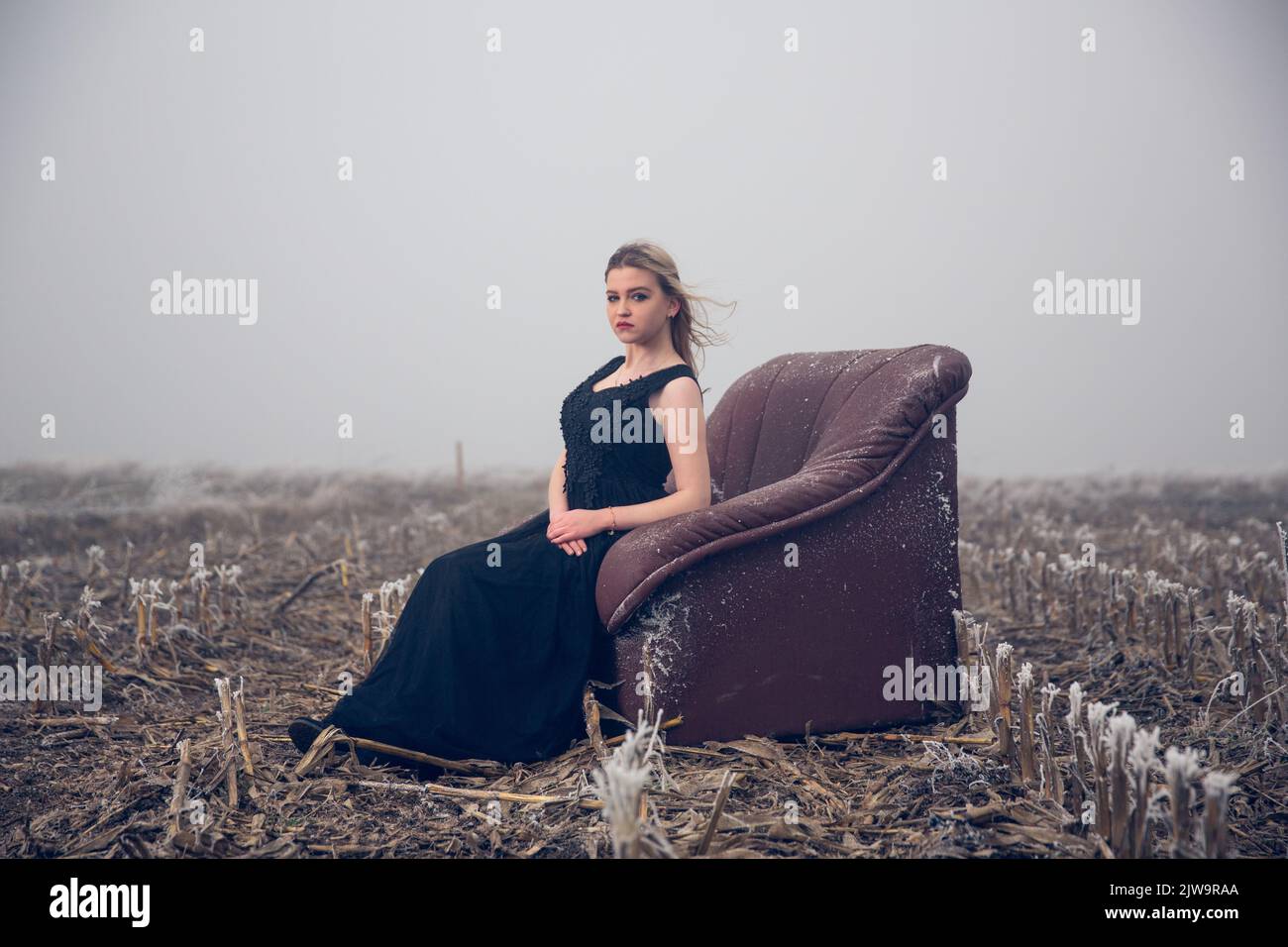 A Pretty blonde female in a dress sitting on a couch in the field Stock ...