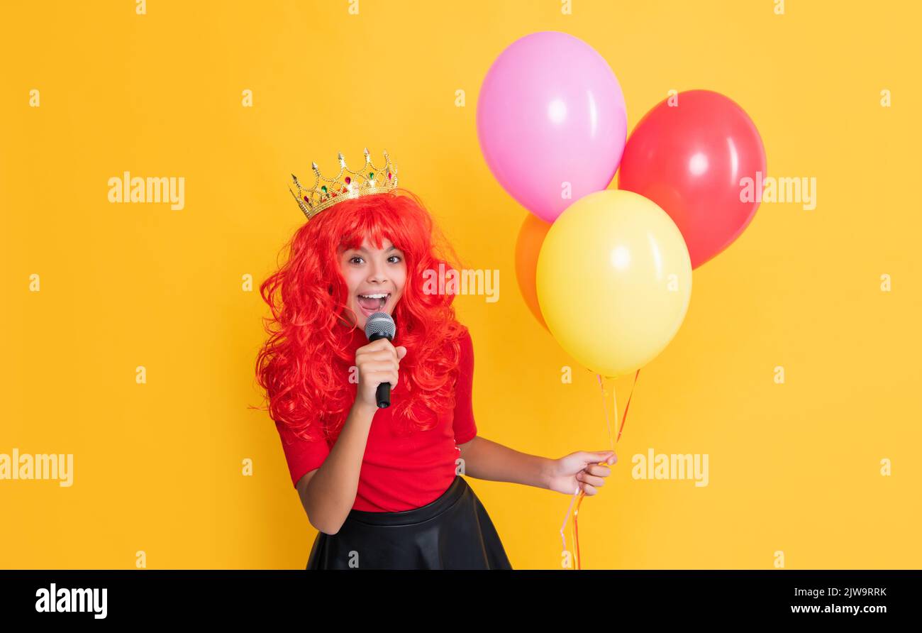 glad child in crown with microphone and party balloon on yellow ...