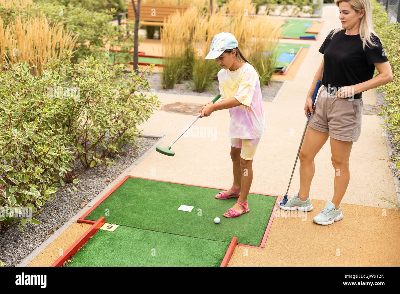 mother and daughter playing mini golf, children enjoying summer ...