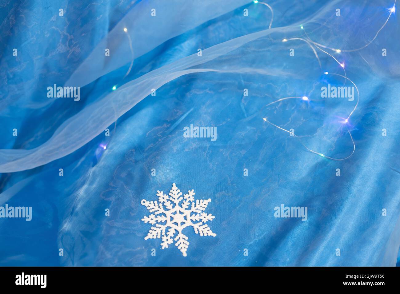 White snowflake cut out from tracing paper on blue background, top view ...