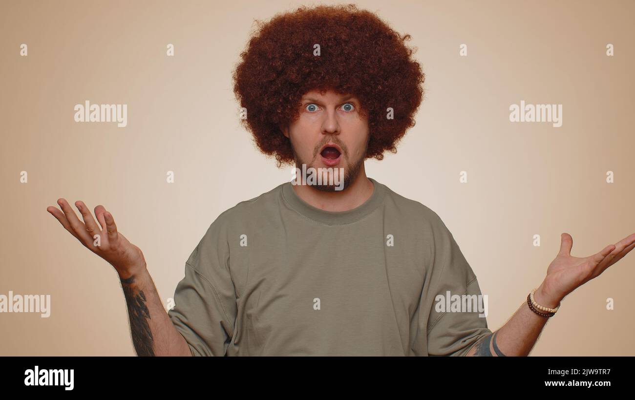 Excited amazed man 30s in t-shirt touching head and showing explosion ...