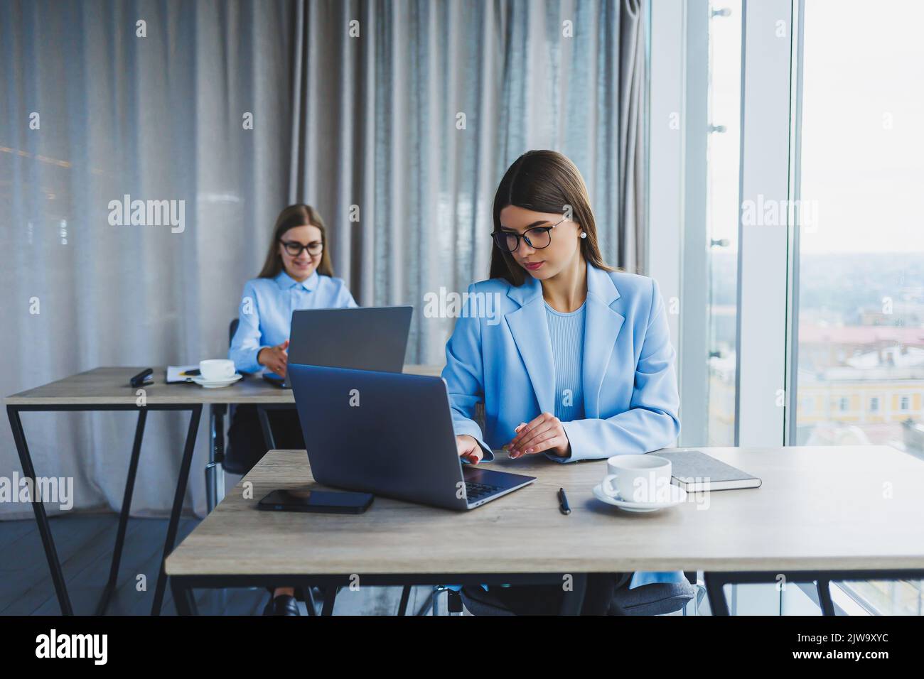 Two beautiful young business women are working and discussing work ...