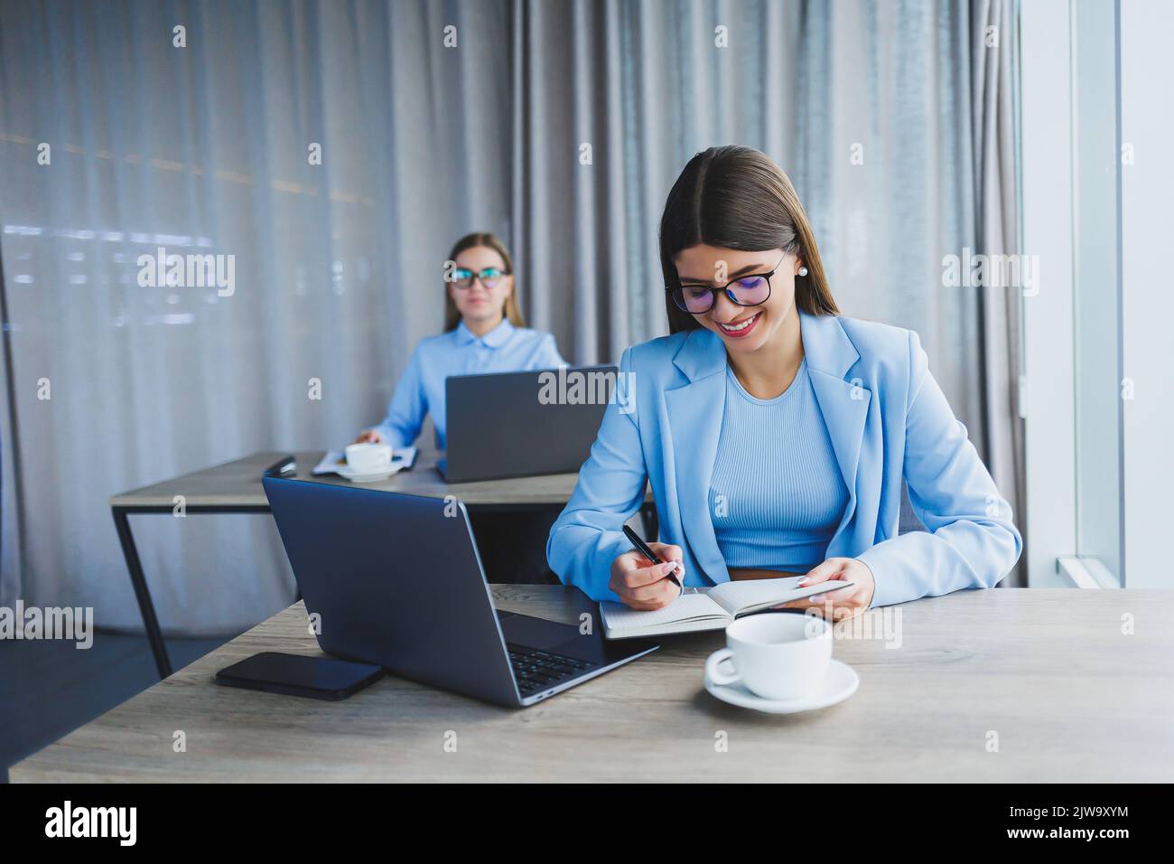 Two beautiful young business women are working and discussing work ...