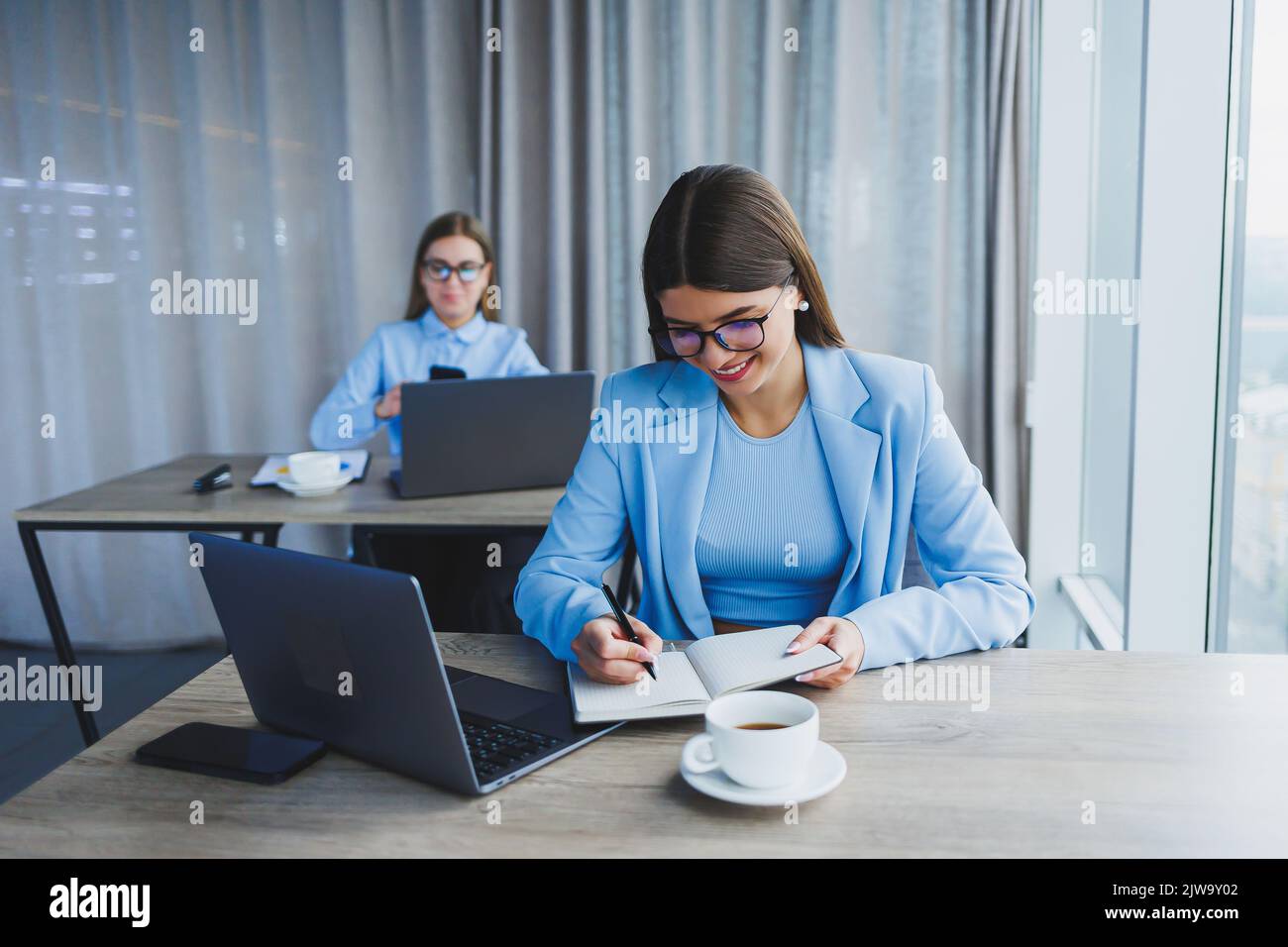 Two beautiful young business women are working and discussing work ...