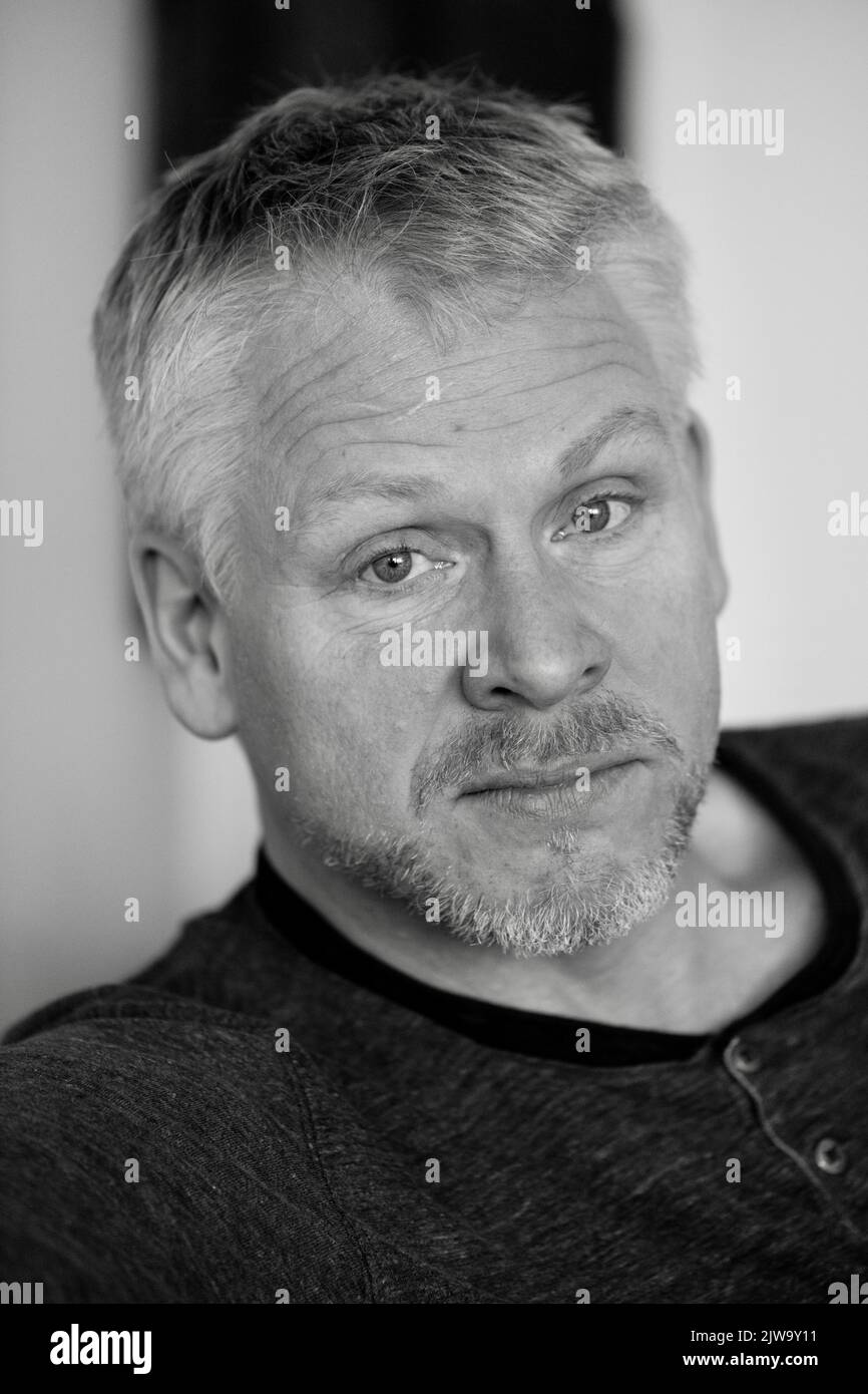 A vertical grayscale portrait of a handsome Caucasian adult man with a ...