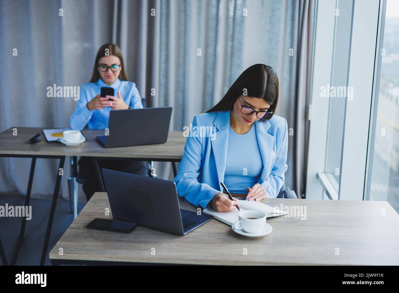 Two beautiful young business women are working and discussing work ...