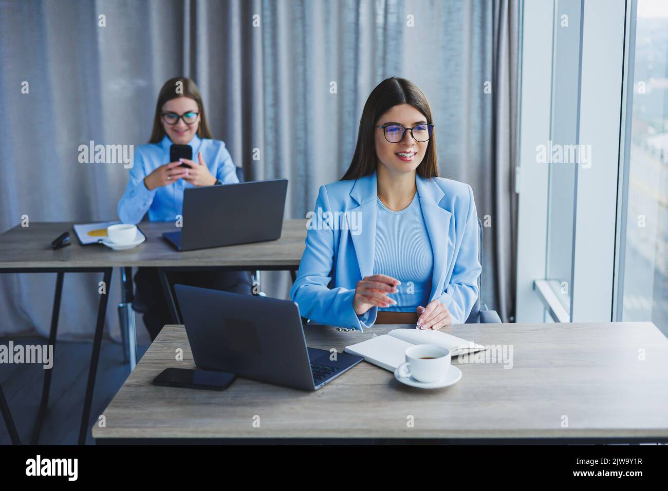 Two beautiful young business women are working and discussing work ...