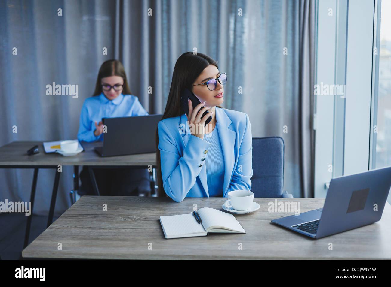 Two beautiful young business women are working and discussing work ...