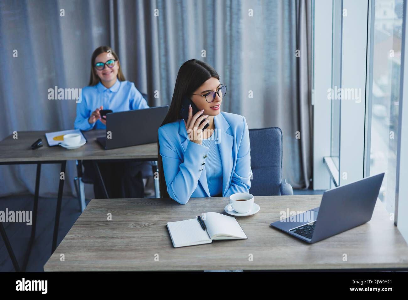 Two beautiful young business women are working and discussing work ...