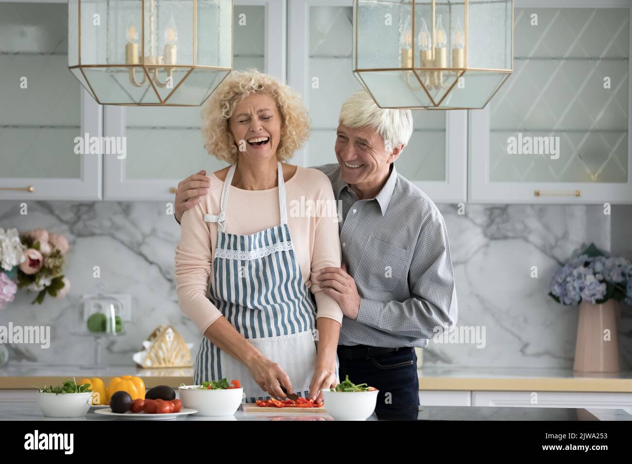 Cheerful mature couple cooking healthy meal for dinner together Stock ...