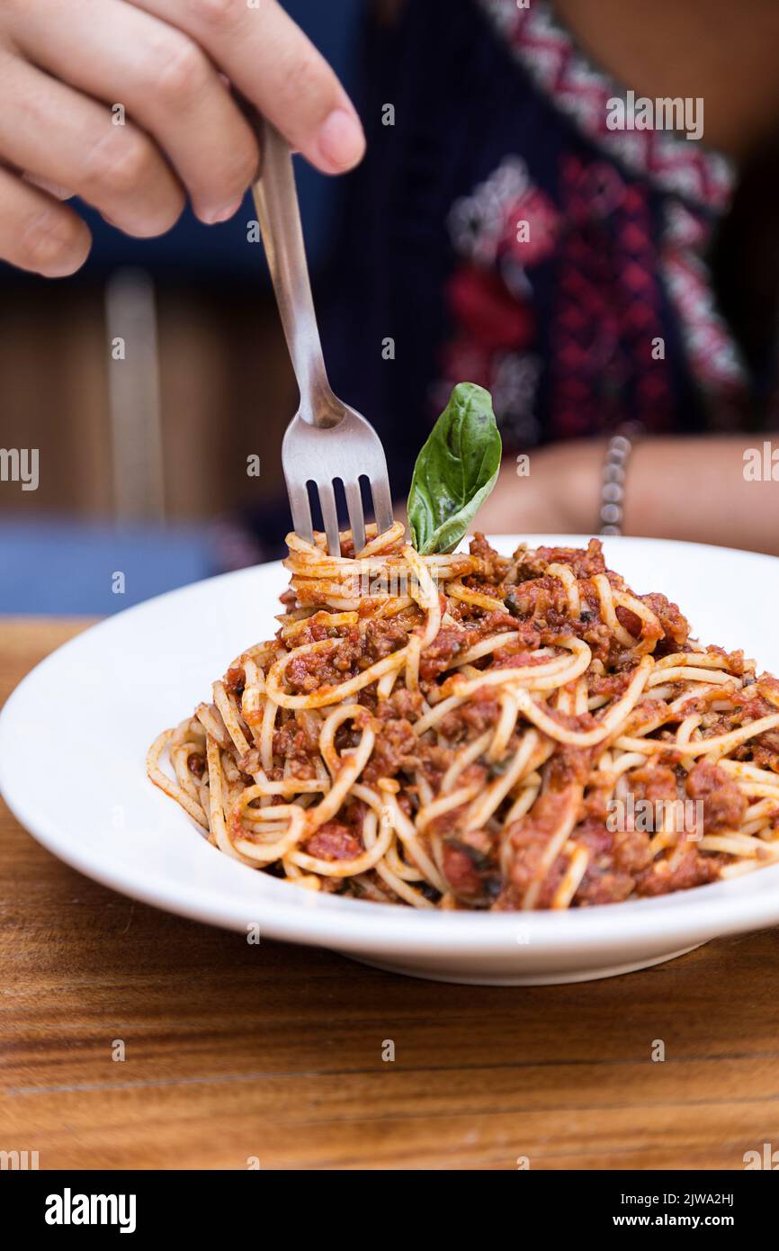Woman's hand holding fork while eating bolognese pasta. Italian ...