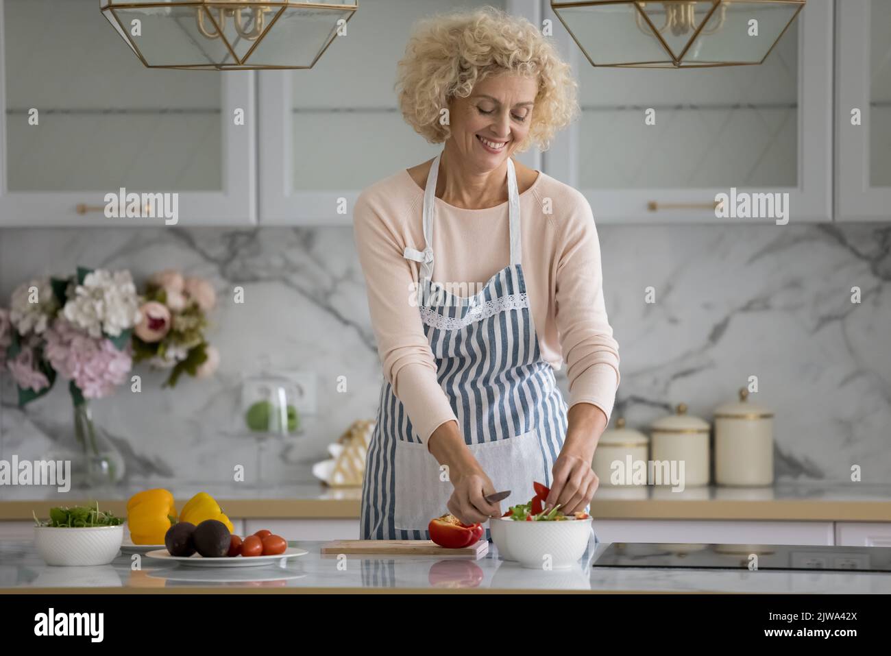 Happy pretty middle aged chef woman slicing fresh vegetables Stock ...