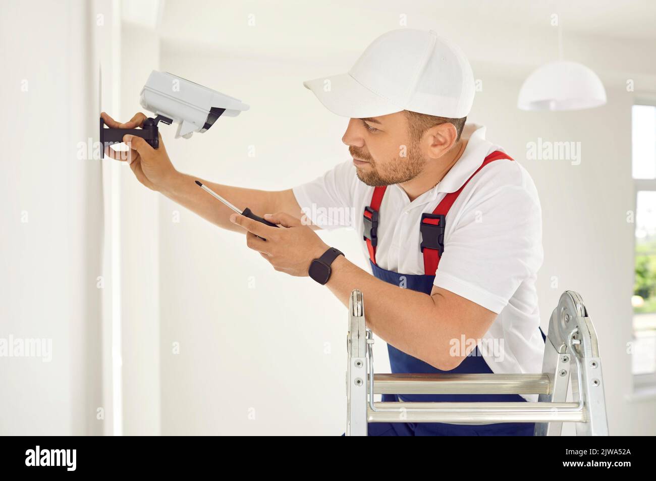 Electrician worker installs and screws surveillance video camera on ...