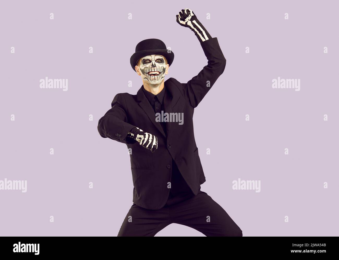Cheerful man with skeleton makeup on his face having fun dancing at ...