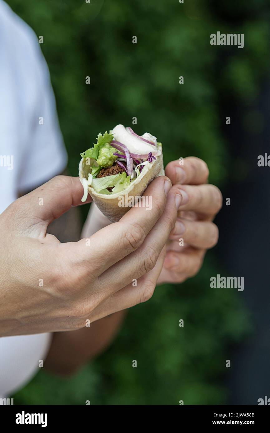 Woman eating a falafel, onion and guacamole taco in a restaurant Stock ...