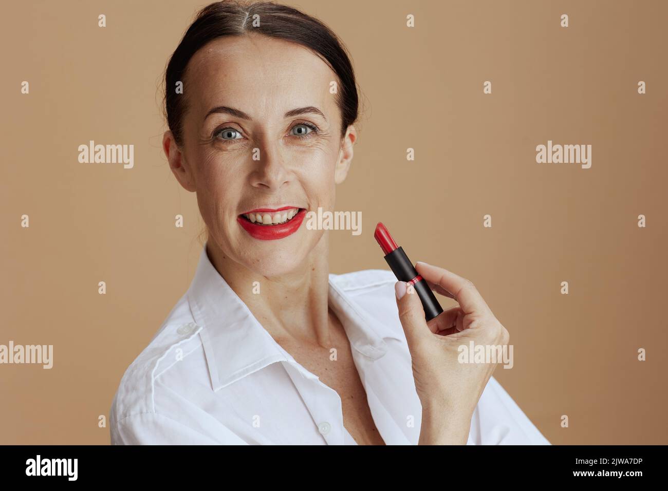 modern middle aged woman with red lipstick in white shirt on beige ...