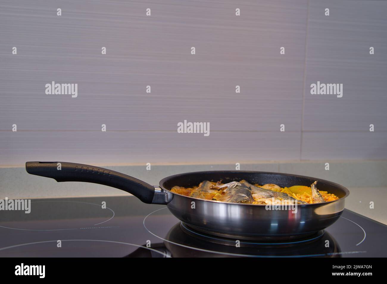 The cooking process of a fish dish in a cooking pan placed on a stove ...