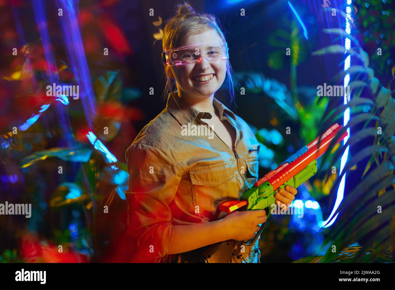 smiling modern child with toy gun and futuristic glasses in virtual ...
