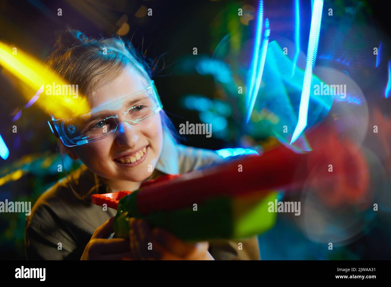 happy stylish child with toy gun and futuristic glasses in virtual ...