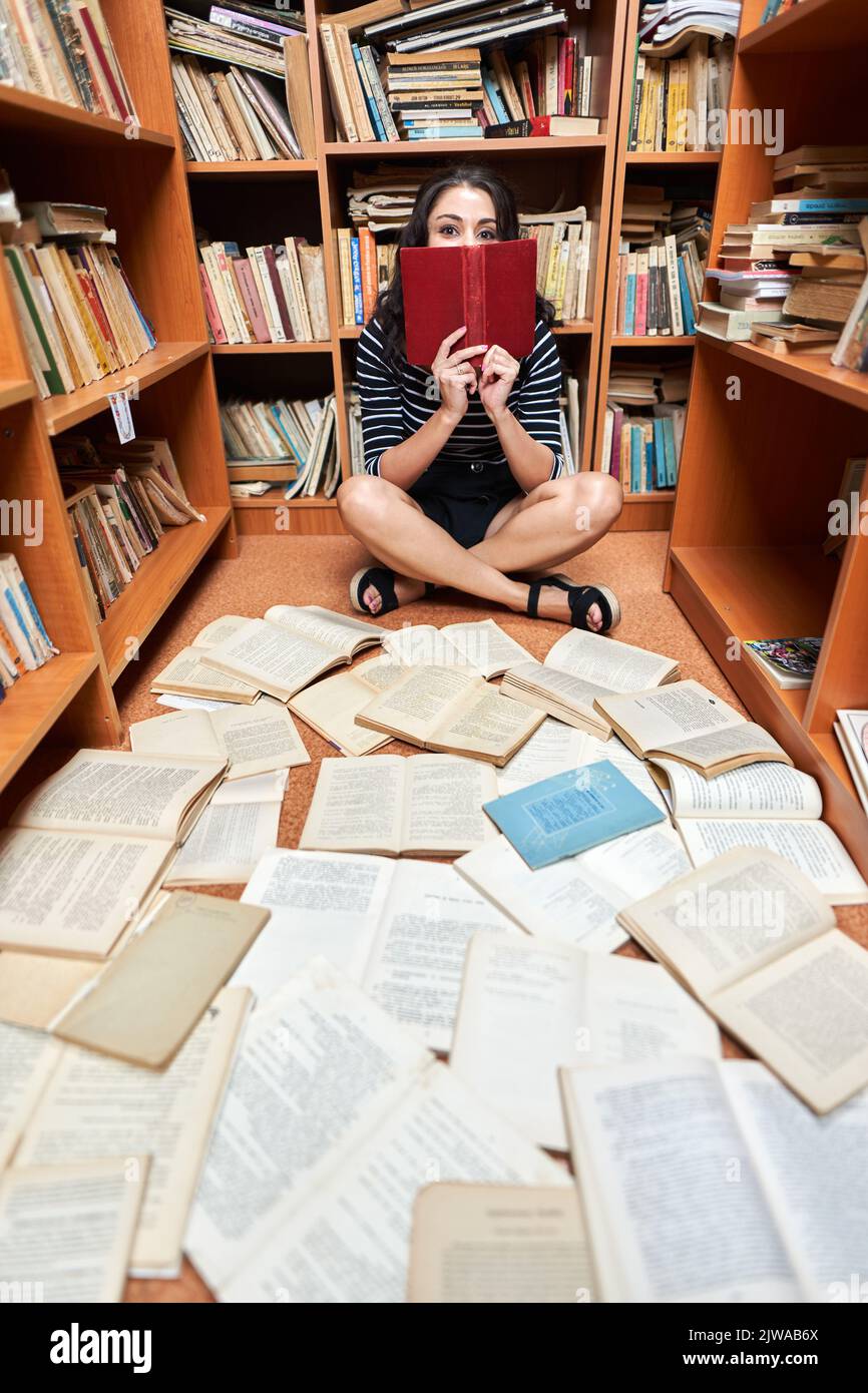 Attractive young woman in striped top and black mini skirt in a library ...