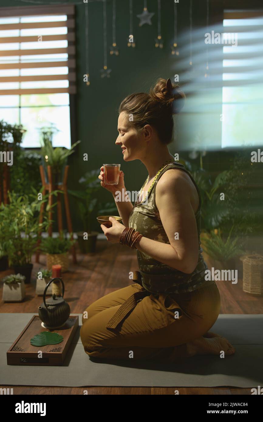 happy modern middle aged woman with tea in the modern green living room ...