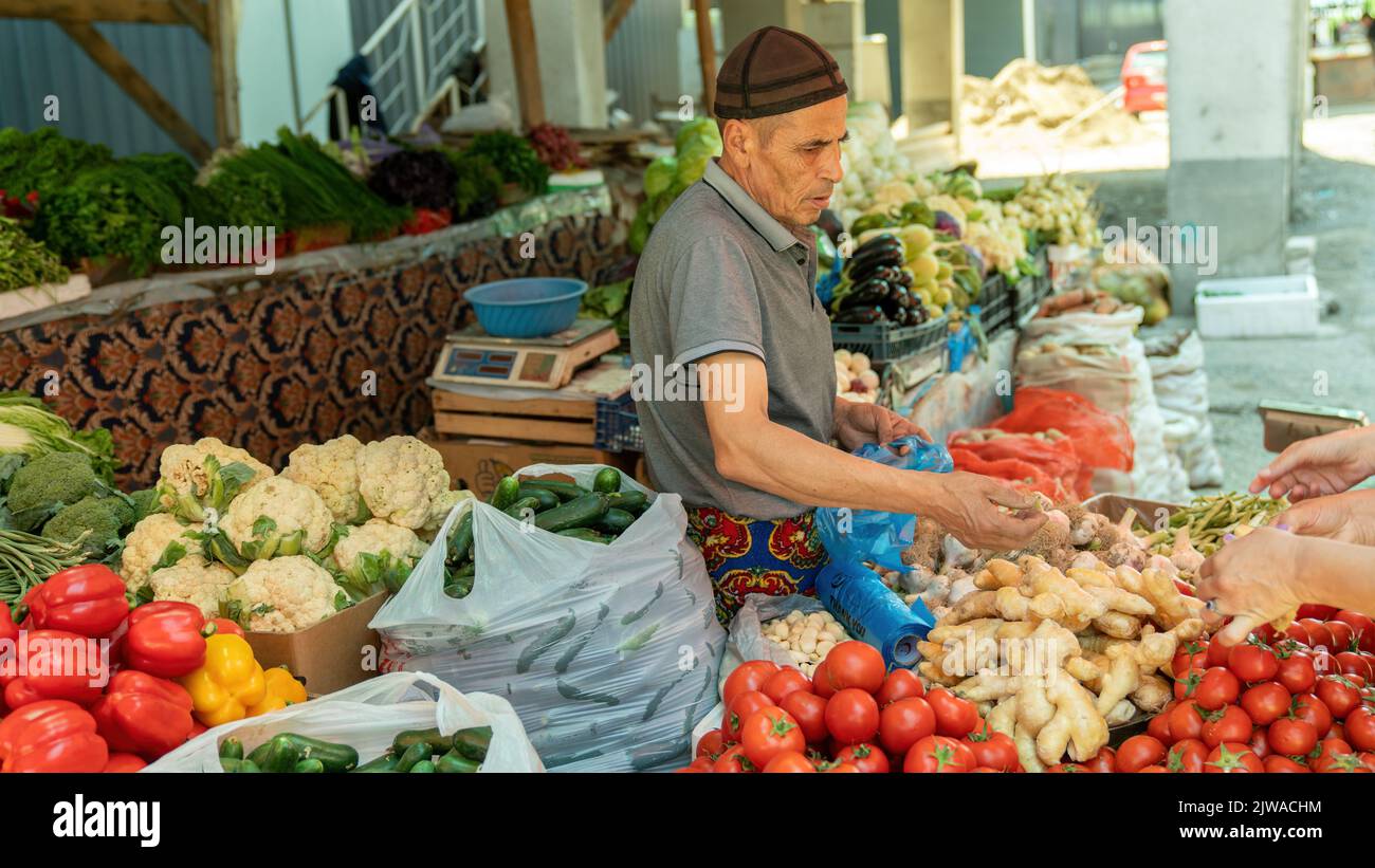 Osh, Kyrgyzstan - May 2022: At Osh market, a local trader sells fresh ...