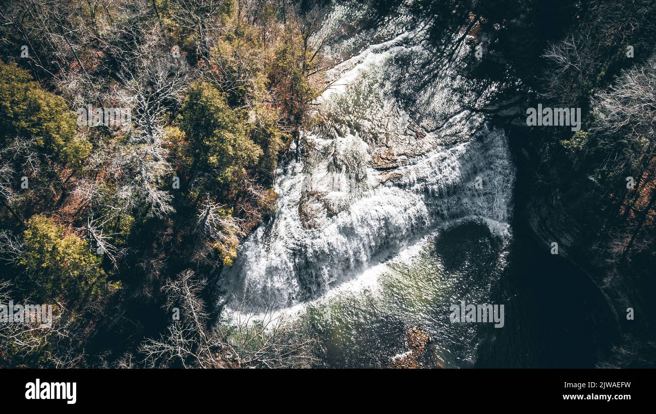 A top view of a beautiful waterfall in forest between large rocks under ...