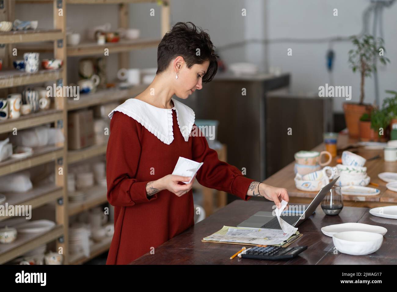 Young female entrepreneur pottery studio owner doing bookkeeping ...