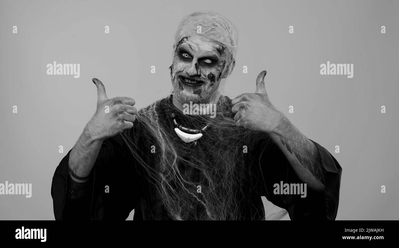 Sinister man with scary Halloween zombie makeup in costume raises ...