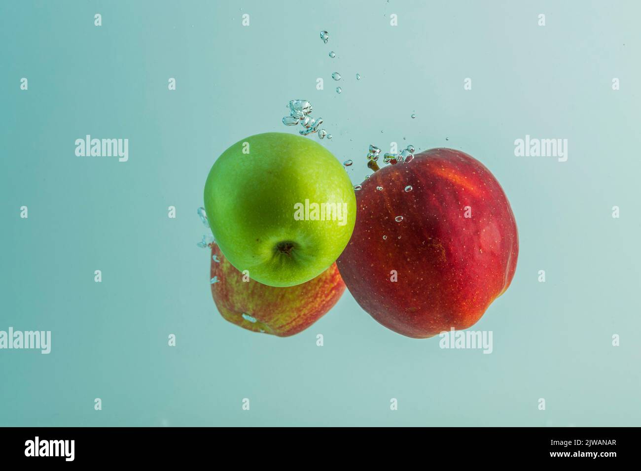 Close up view of red and green apples falling into water isolated on ...