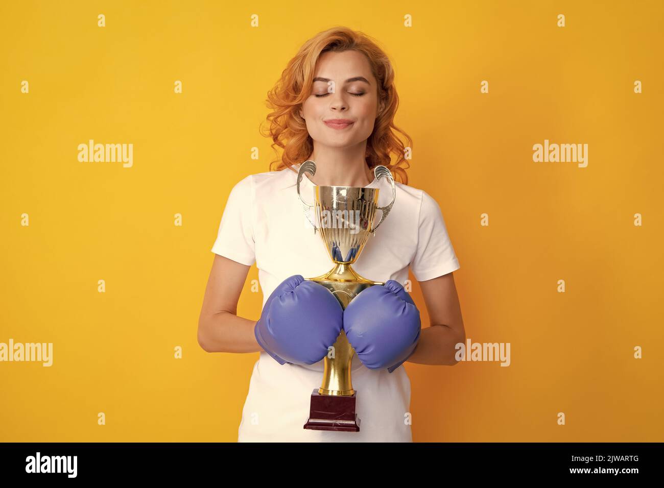 Woman in boxing gloves hold champion winner cup trophy. Cheerful woman ...