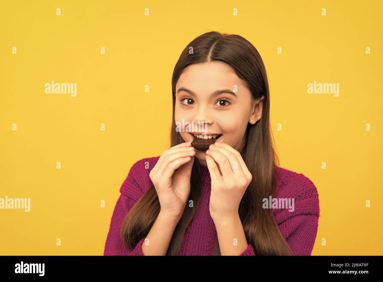 Happy kid enjoy eating delicious chocolate snack yellow background ...