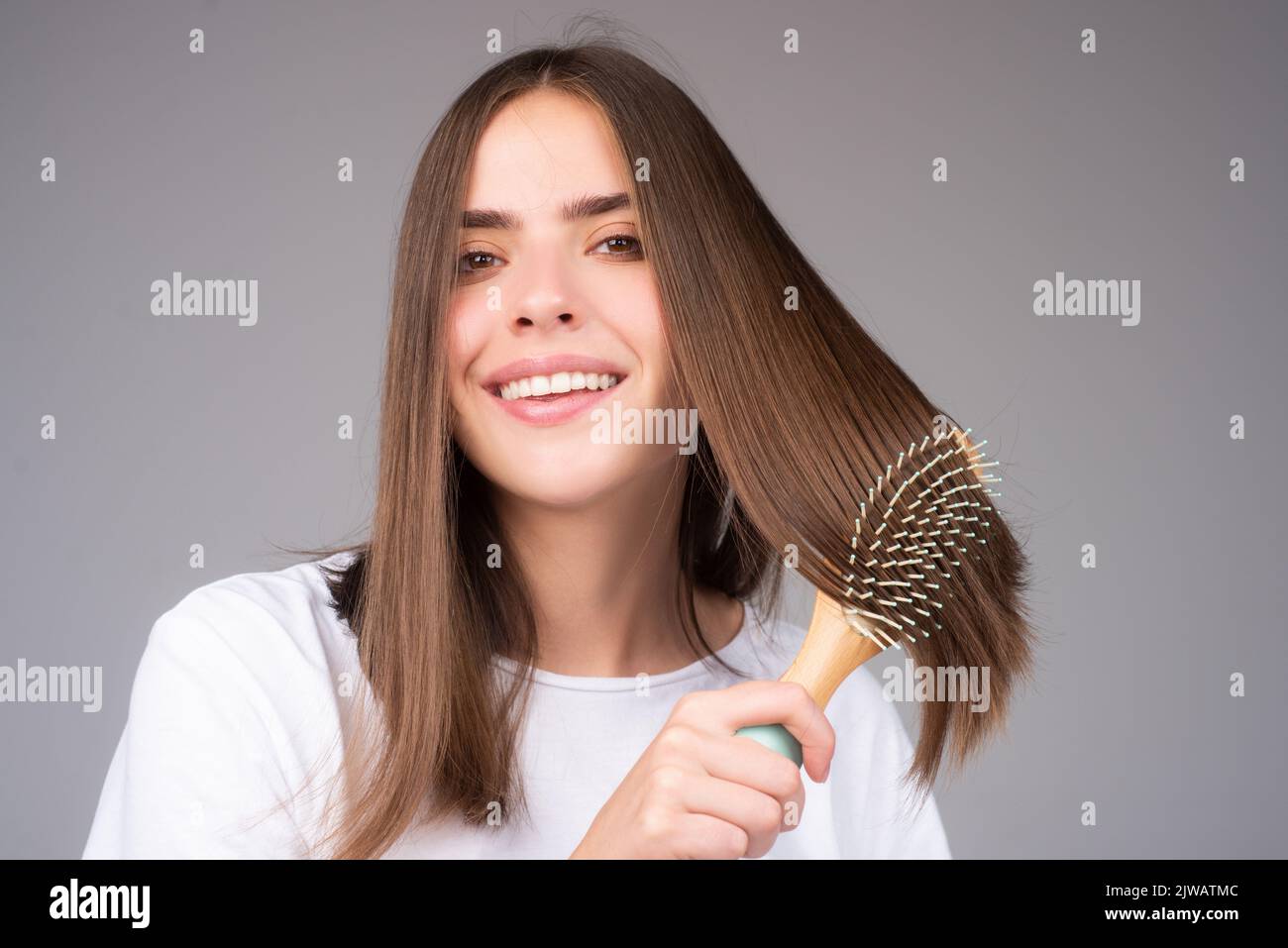 Portrait of beautiful young woman combing her hair, smiling. Female ...