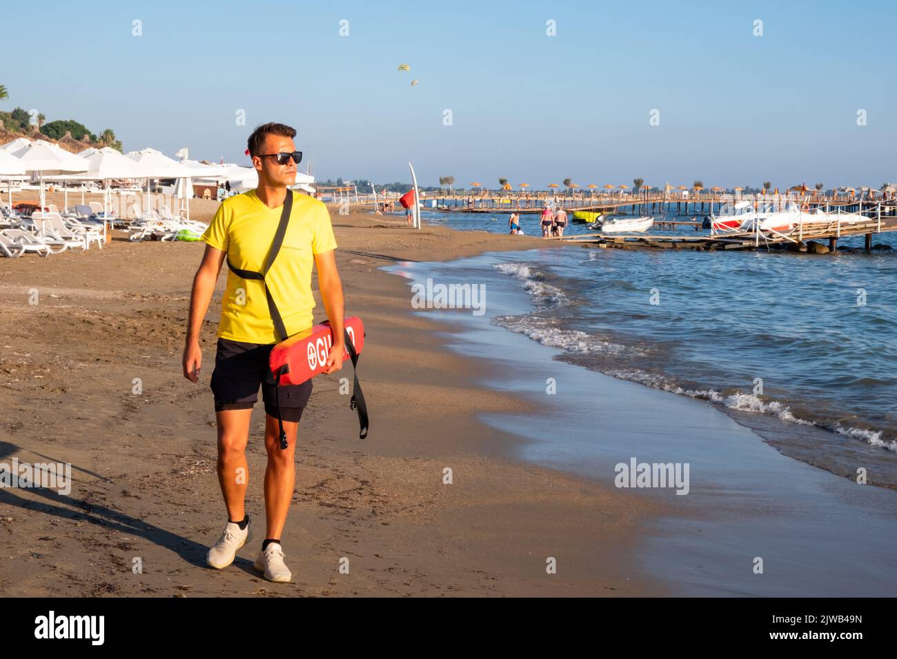 Male lifeguard on the Mediterranean beach watching people in water ...