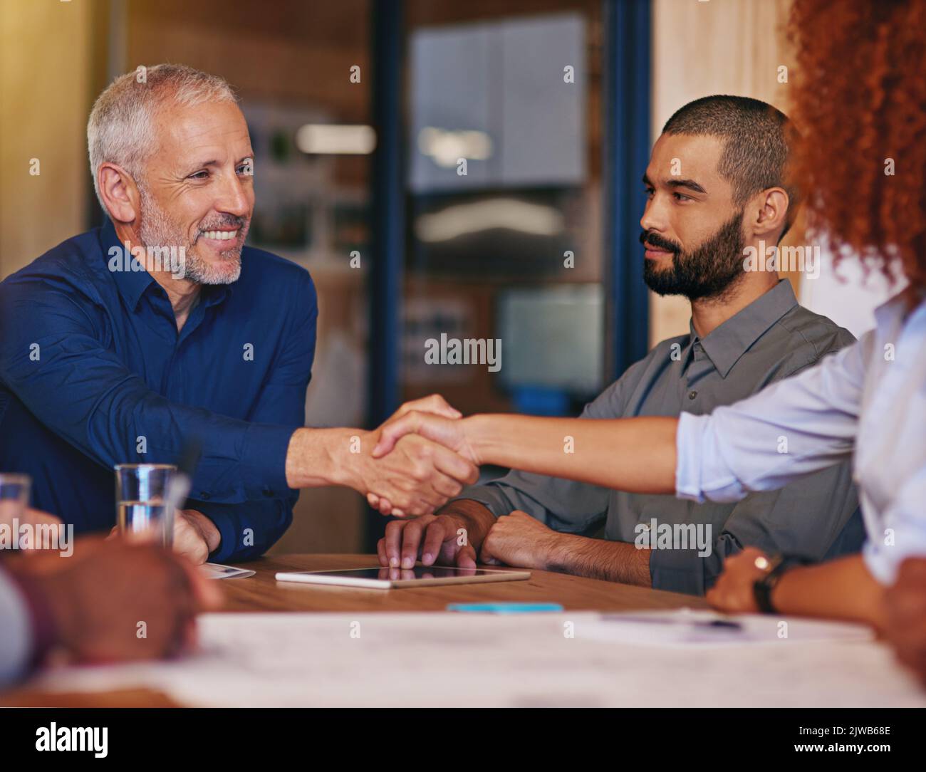 Welcoming a new member to the team. colleagues shaking hands in an ...