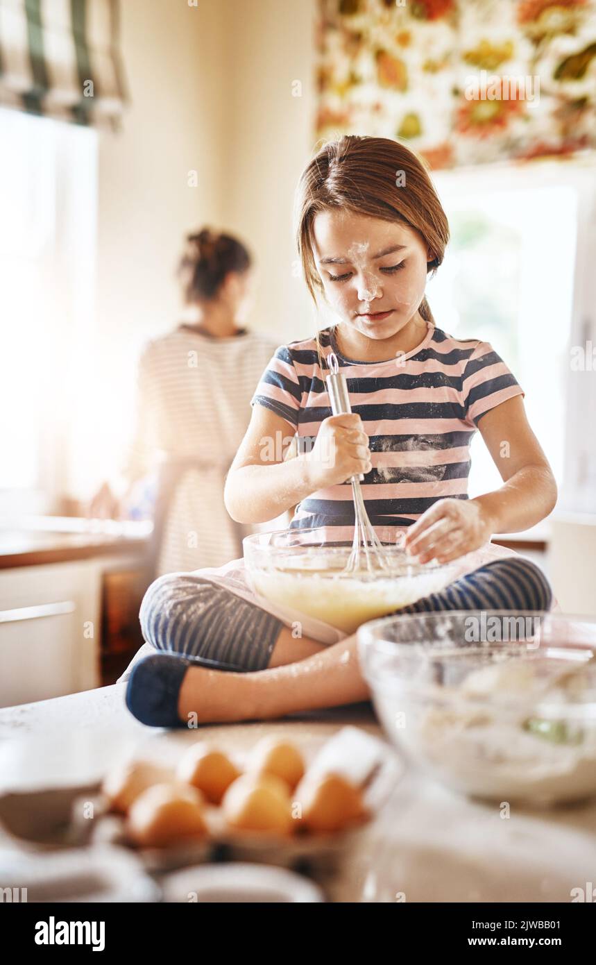 Shes a busy little baker. a little girl baking with her mother in the ...