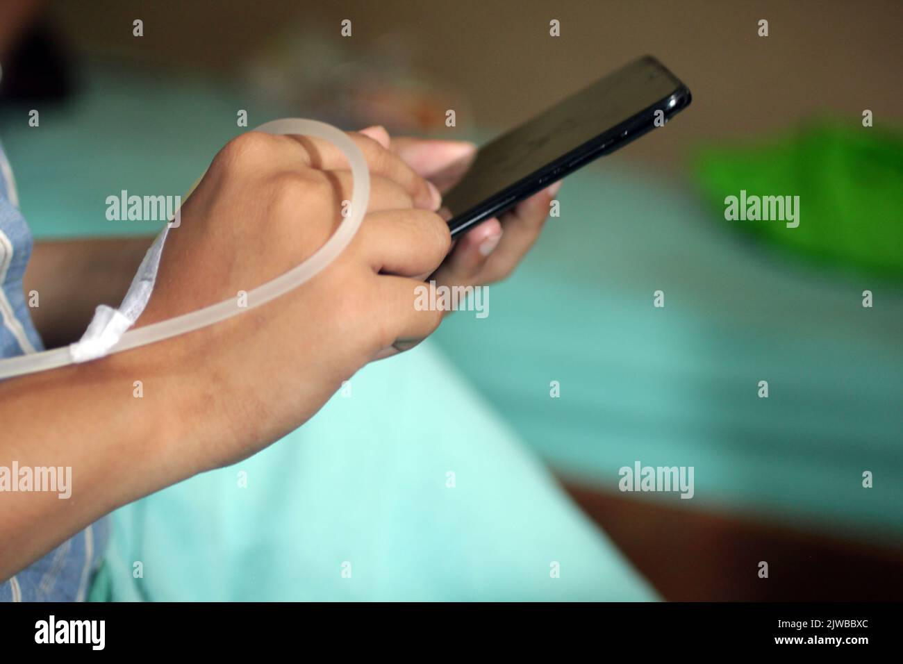 Female patient checking touchscreen phone sending messages with iv line ...