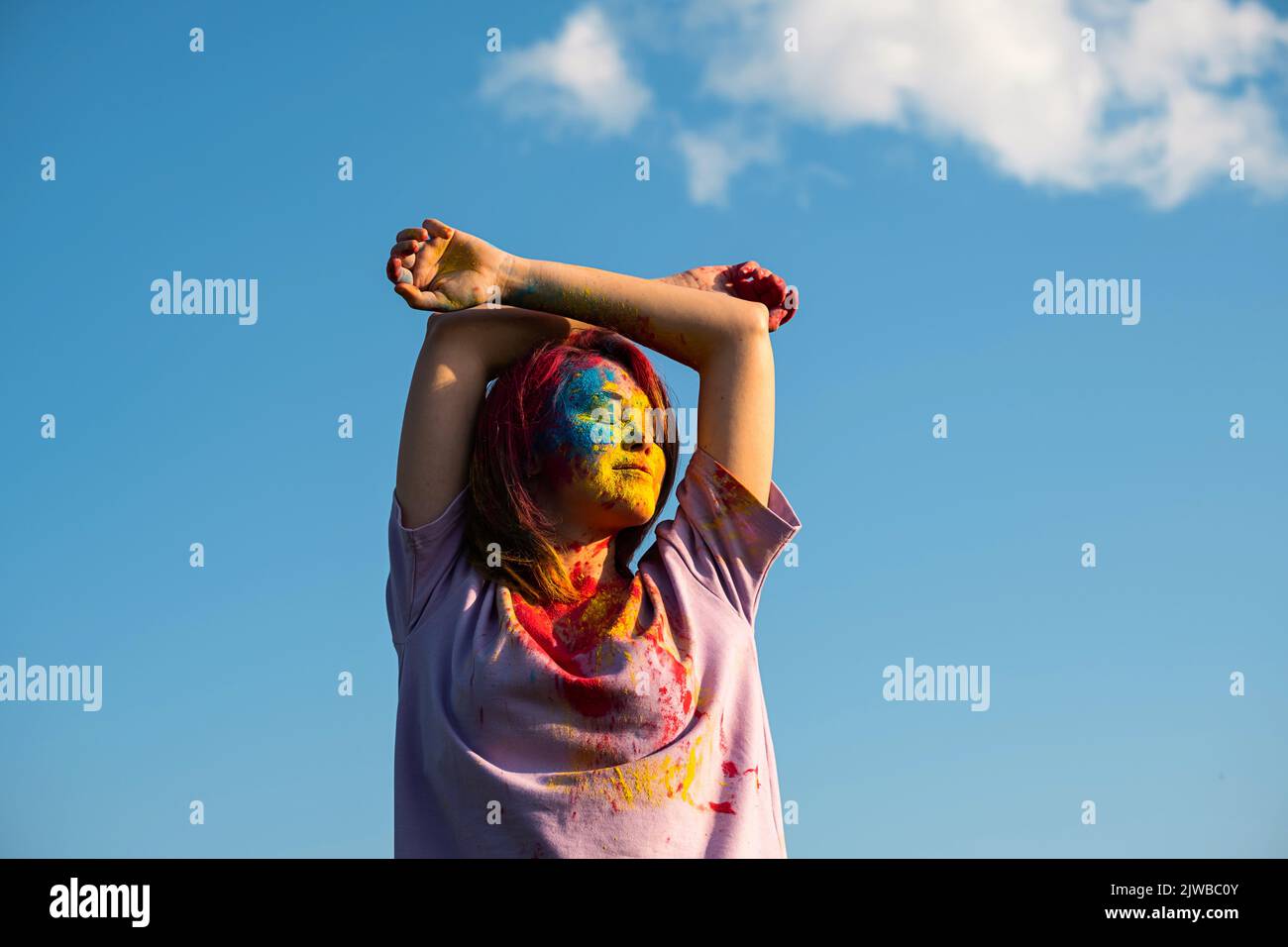 Woman covered in holi powder against blue sky. Holi colours festival ...