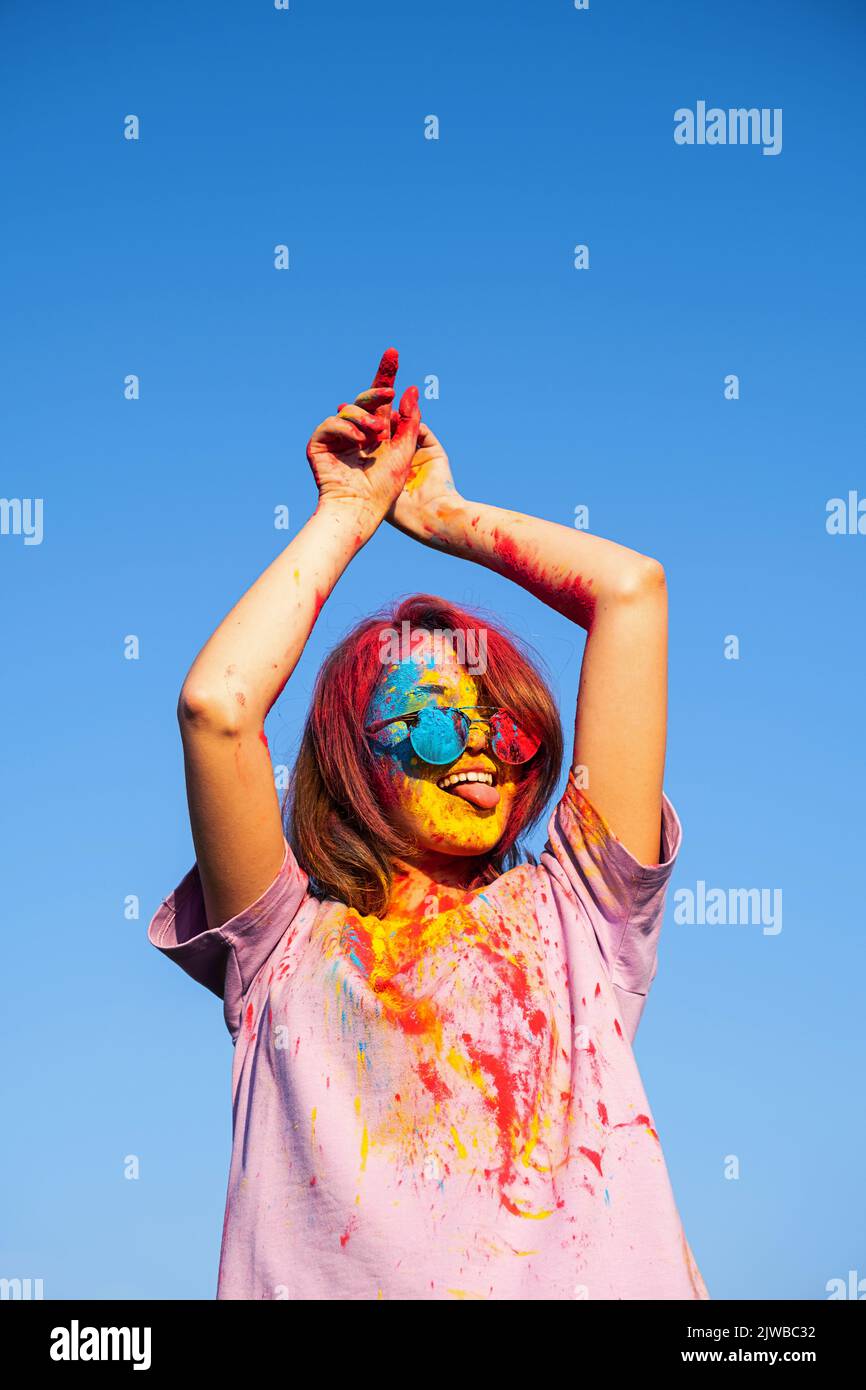 Woman covered in holi powder against blue sky. Holi colours festival ...