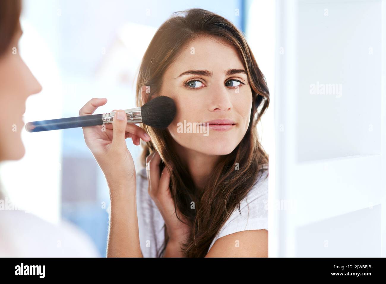 Brightening up her cheeks. a beautiful young woman applying makeup with ...