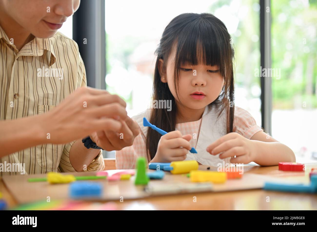 Little cute Asian girl playing play dough with her male primary school ...